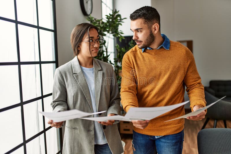 Two Business Workers with Serious Expression Reading Paperwork Standing ...