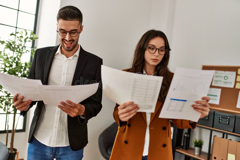 Two Business Workers Smiling Happy Reading Paperwork Standing at the ...