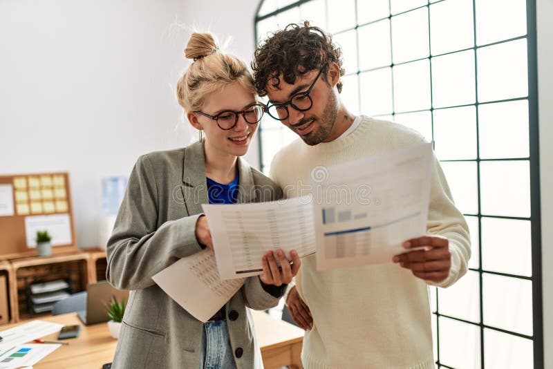 Two Business Workers Smiling Happy Reading Paperwork Standing at the ...