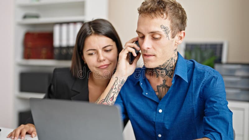 Two Business Workers Using Laptop Talking on Smartphone at the Office ...