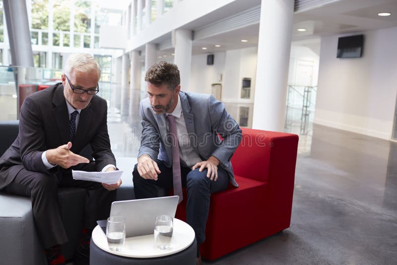 Two Businessmen Discuss Document in Lobby of Modern Office Stock Photo ...