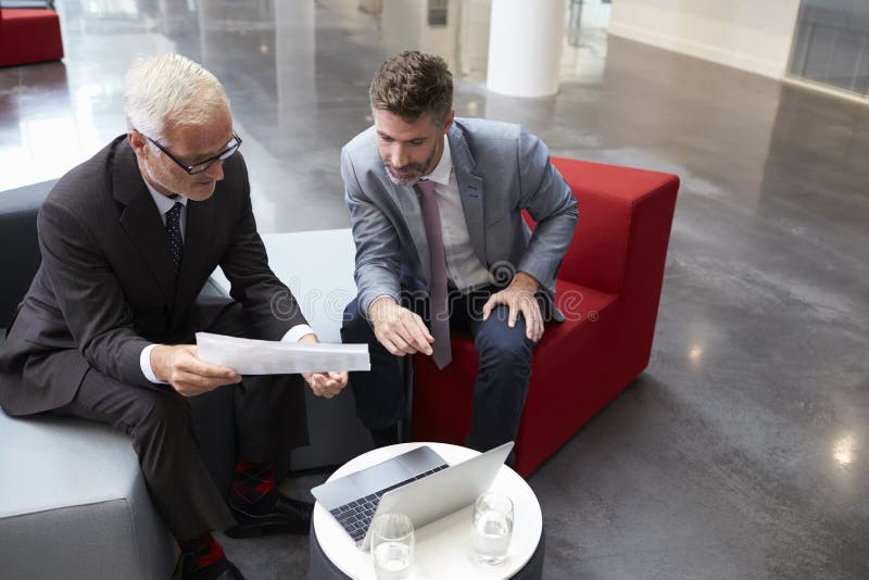 Two Businessmen Discuss Document in Lobby of Modern Office Stock Photo ...