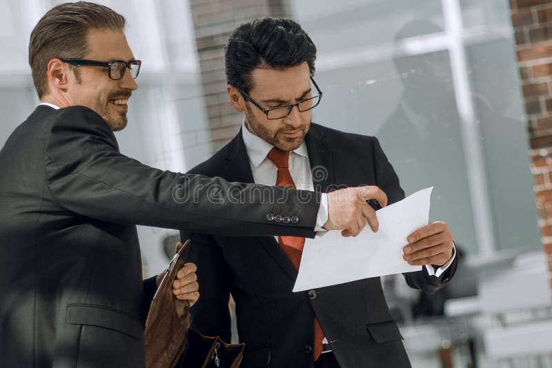 Two Businessmen Discuss the Document Standing in the Office Lobby ...