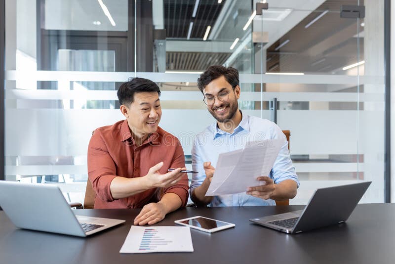 Two Businessmen Discussing Documents at a Modern Office with Technology ...