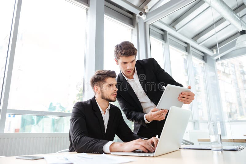 Two Businessmen Using Laptop and Tablet in Office Together Stock Photo ...