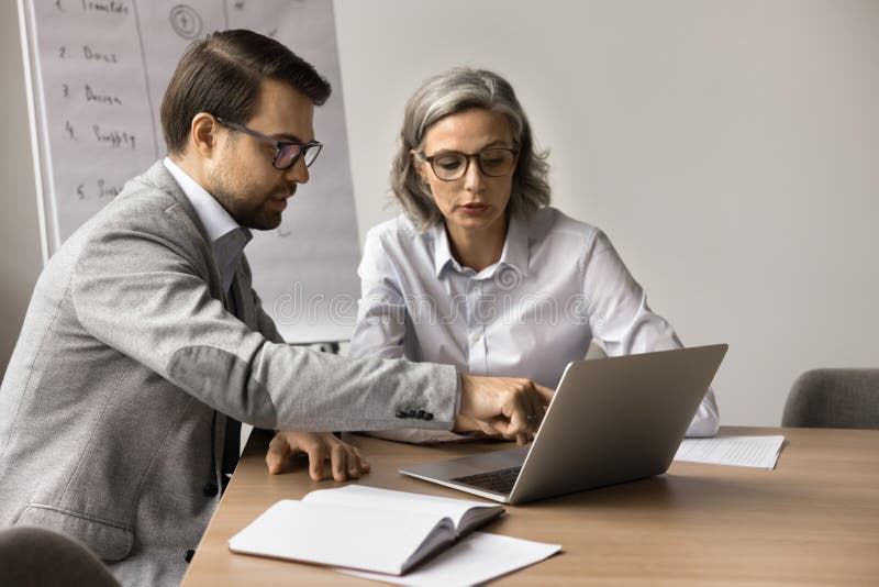 Two Businesspeople Sitting at Table Focused on Laptop Screen Stock ...