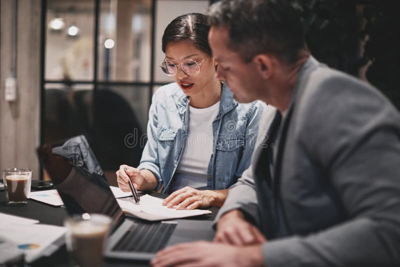 Two Businesspeople Sitting at a Table and Going Over Paperwork Stock ...