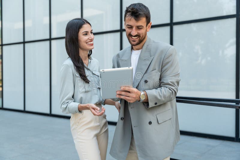 Two Businesspeople Standing Outside of Modern Office Building, Using ...