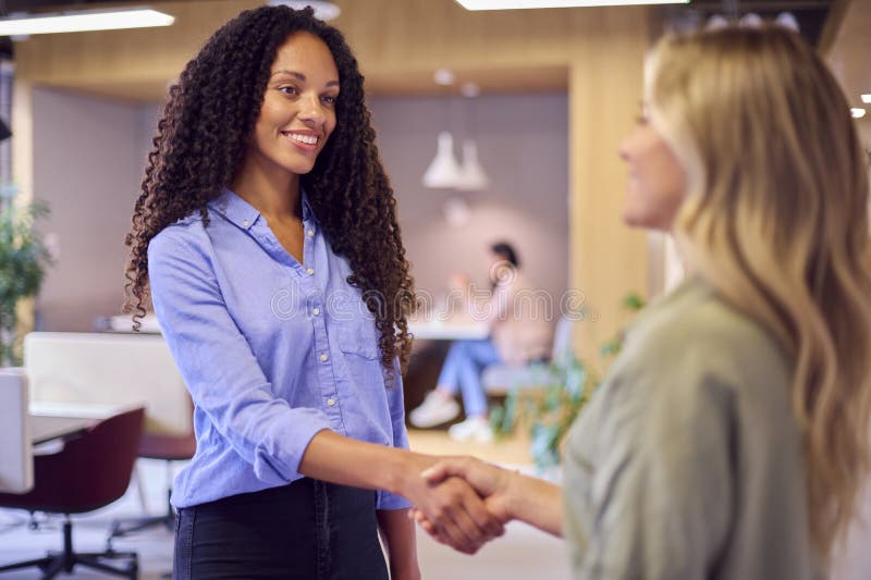 Two Businesswomen Meeting and Shaking Hands in Modern Open Plan Office ...