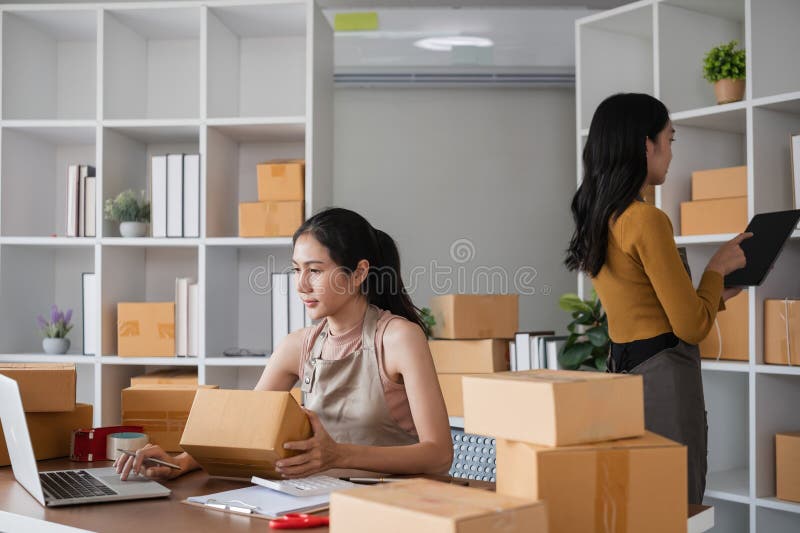 Two Businesswomen Organizing and Preparing Packages for Shipping in ...