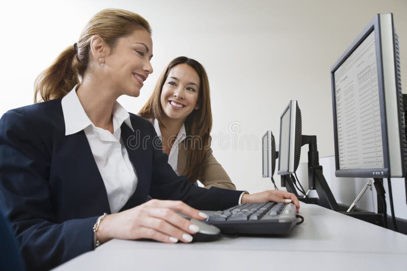 Two Businesswomen Smiling Over Computers Stock Photo - Image of formal ...