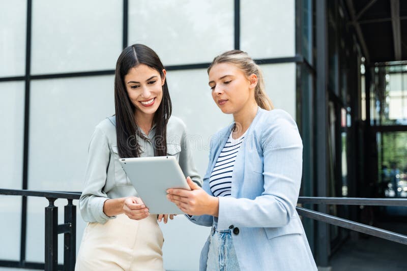Two Businesswomen Standing Outside of Modern Office Building, Using ...