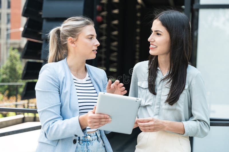 Two Businesswomen Standing Outside of Modern Office Building, Using ...
