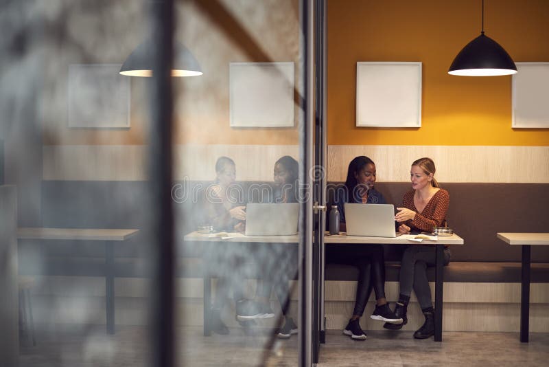 Two Businesswomen Working Late in Open Plan Office Using Laptop Stock ...