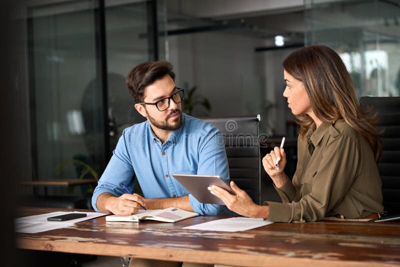 Two Busy Colleagues Working Together Talking Using Tab Device in Office ...