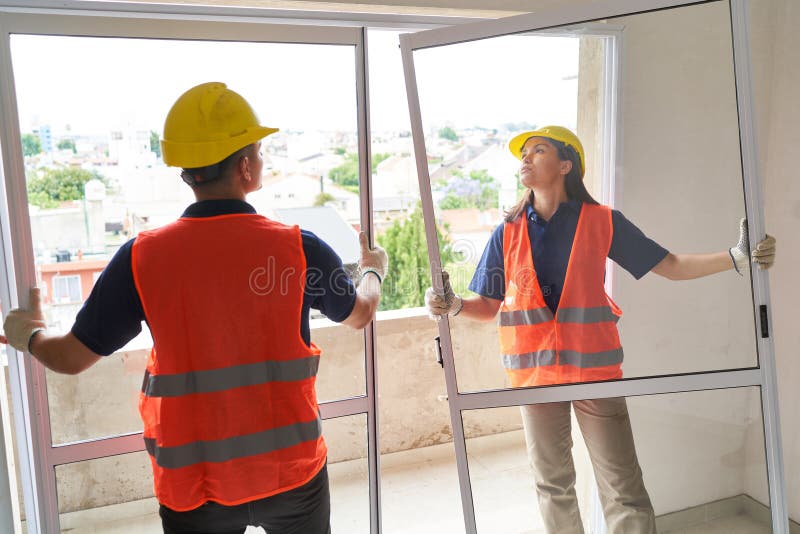 Two Carpenters Wearing Safety Vest Installing Window Frames in House ...