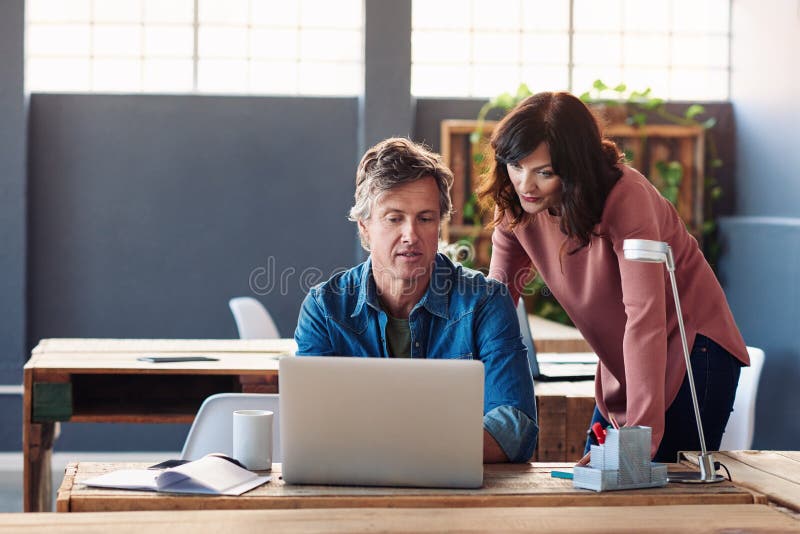 Two Coworkers Talking Together Over a Laptop in an Office Stock Image ...