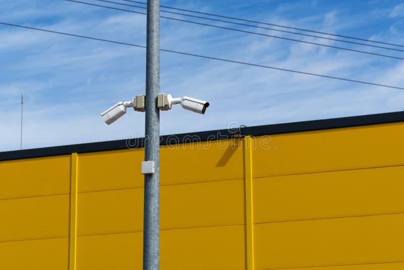 Two Cctv Cameras on a Pole Against a Yellow Wall and Sky, Security ...