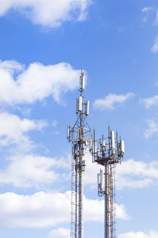 Two Cell Towers Against the Blue Sky with Clouds. Mobile Communications ...