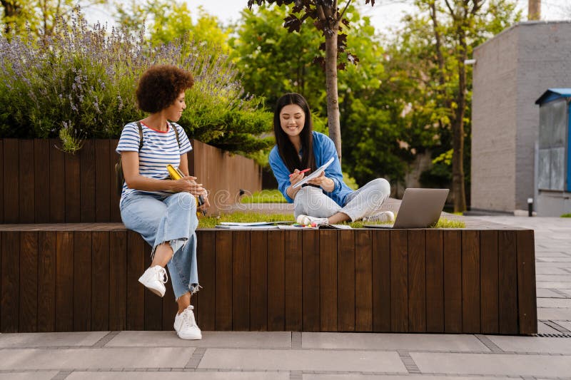 Two Cheerful Female Students Making Notes while Studying Together ...