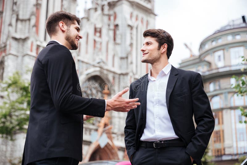 Two Cheerful Young Businessmen Standing and Talking Stock Photo - Image ...