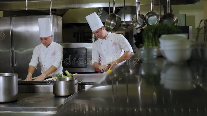 Two Chefs in White Uniforms Work in a Large Professional Kitchen. Stock ...
