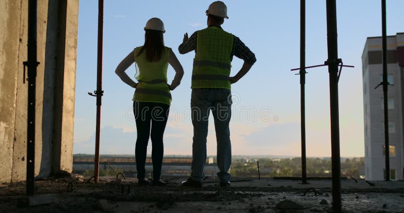 Two Chief Engineer with a Drawing in Hand Looking at the Construction ...