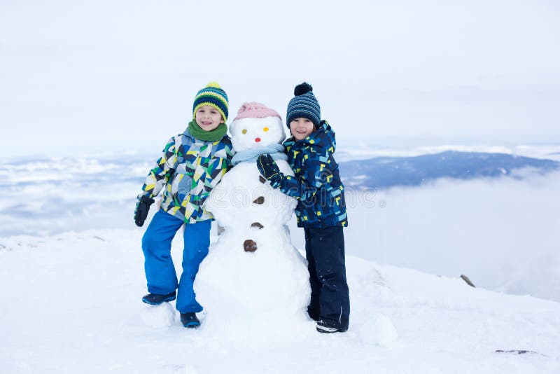 Two Children, Building Snowman on Top of Mountain Stock Image - Image ...