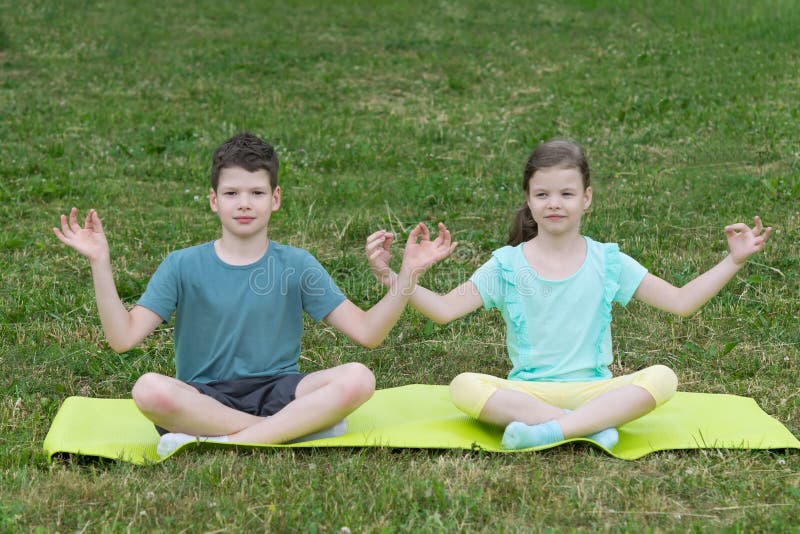 Two Children Doing Yoga Sitting on a Green Lawn Stock Image - Image of ...