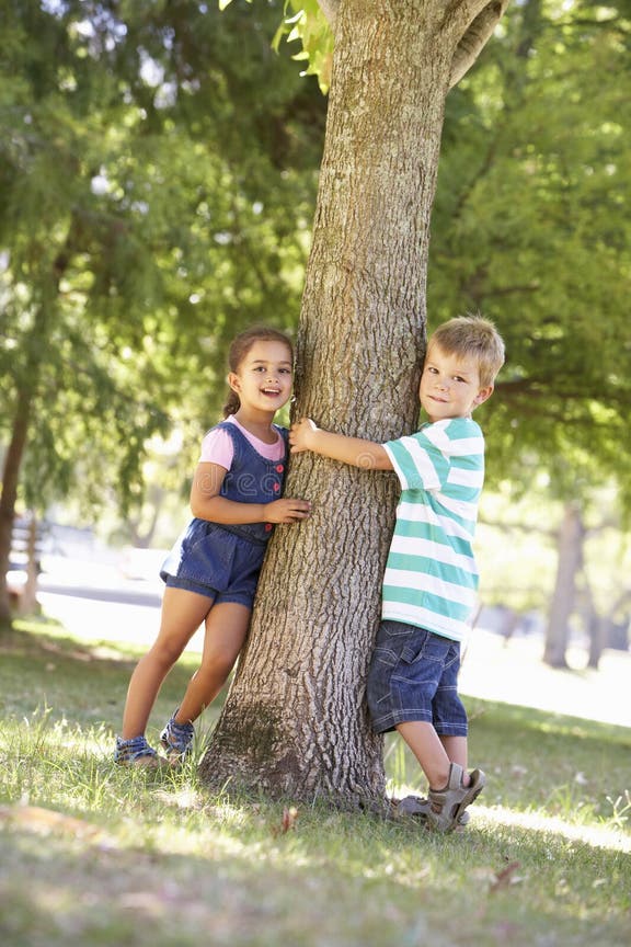 Two Children Hugging Tree in Park Stock Photo - Image of sunny, female ...