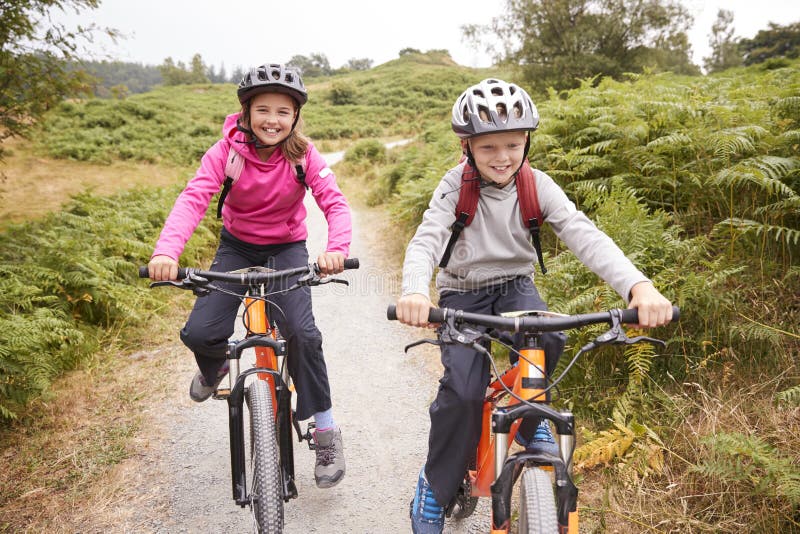 Two Children Riding Mountain Bikes on a Country Path Laughing, Front ...