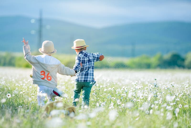 Two Children Running Around the Field with Daisies Holding Hands Stock ...