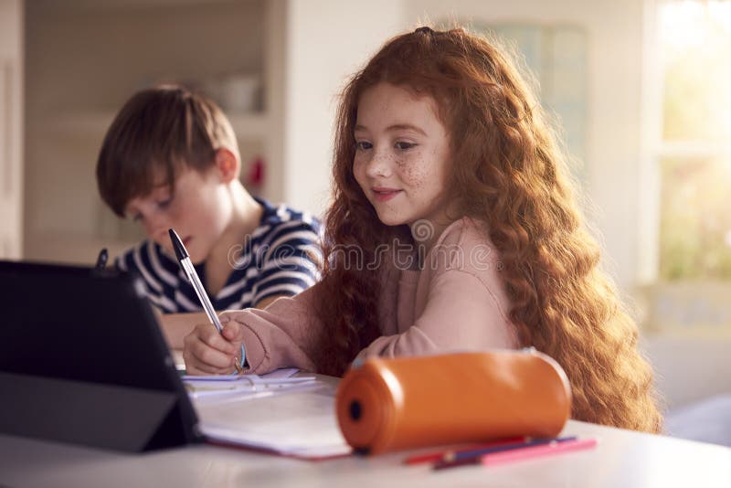 Two Children Sitting at Kitchen Counter Doing Homework Using Digital ...