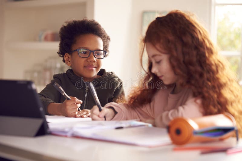 Two Children Sitting at Kitchen Counter Doing Homework Using Digital ...