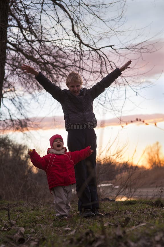 Two children on a sunset stock image. Image of river - 84106815