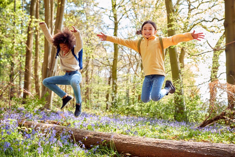 Two Children Walking through Bluebell Woods in Springtime Jumping Over ...