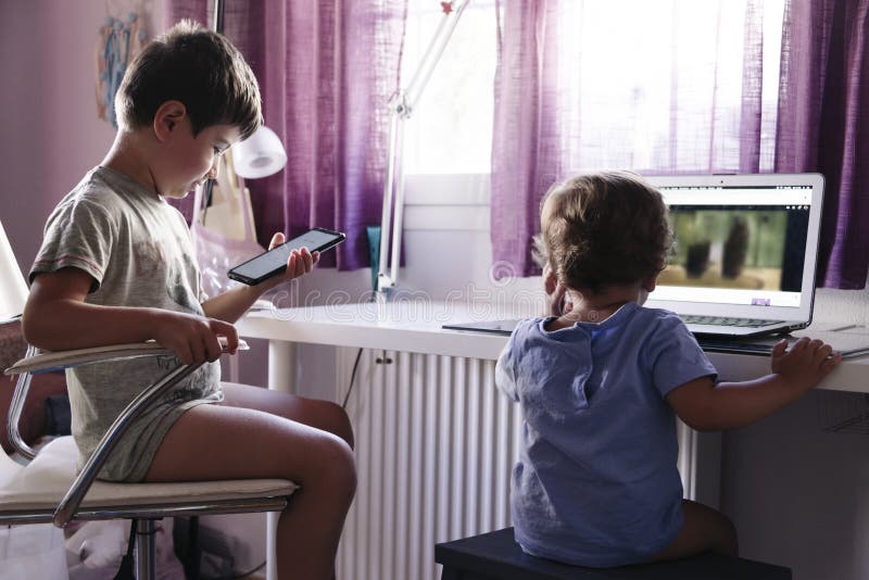 Two Children Watching Videos on Computer and Cell Phone Stock Photo ...