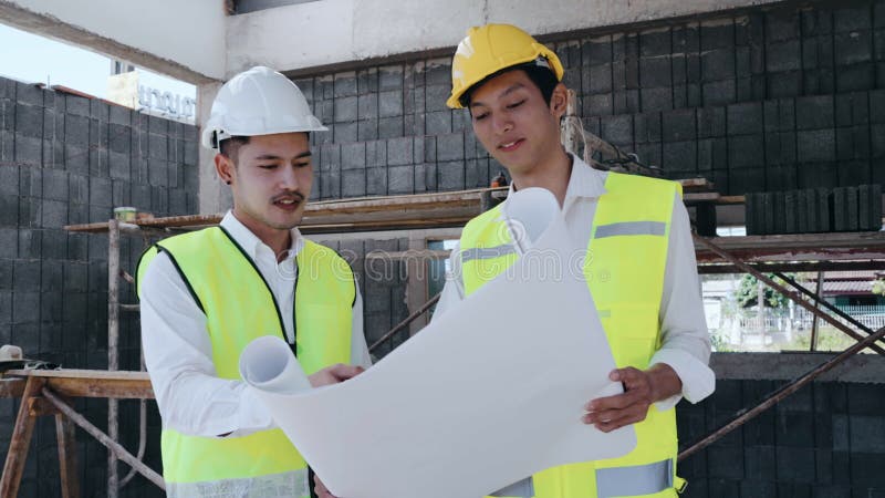 Two Civil Engineers Working on a Project Wearing Safety Helmets are ...