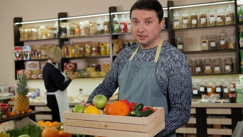 Two Clerks Work in a Grocery Store, a Man Puts Fresh Fruit on the ...