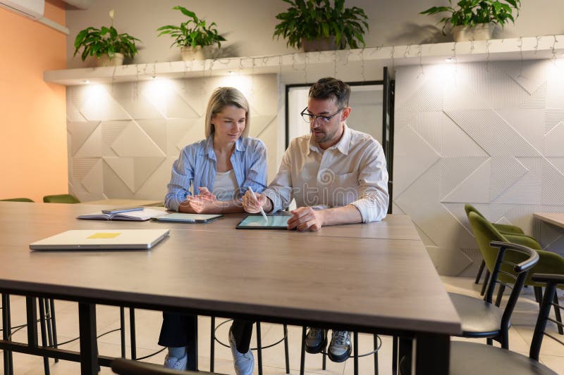 Two Colleagues Collaborating in a Modern Workspace with Digital and ...