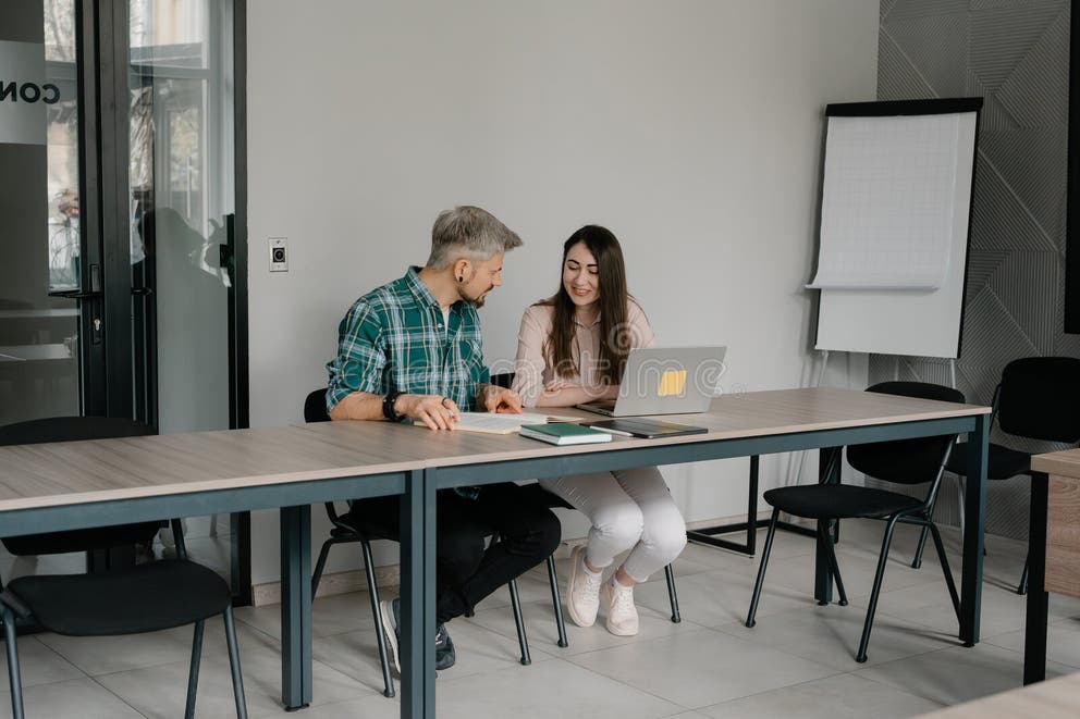Two Colleagues Collaborating at a Workspace with Documents and a Laptop Stock Photo - Image of ...