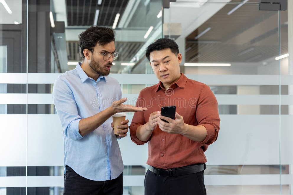 Two Colleagues Debating and Analyzing Data on a Smartphone while ...