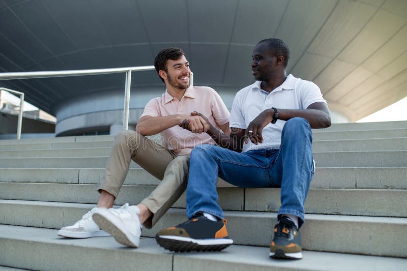 Two Colleagues Sitting Together on Steps and Talking Stock Photo ...