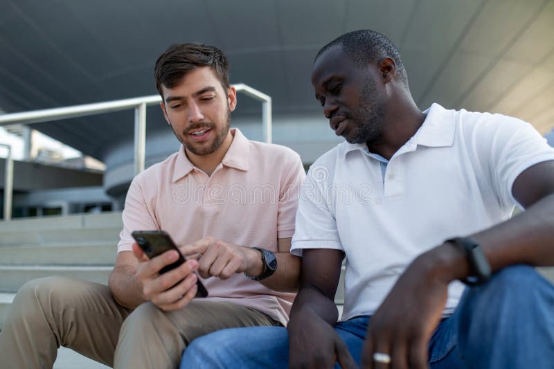 Two Colleagues Sitting Together on Steps and Talking Stock Photo ...