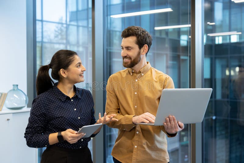 Two Business Colleagues, a Man and a Woman, Collaborate Using a Laptop ...