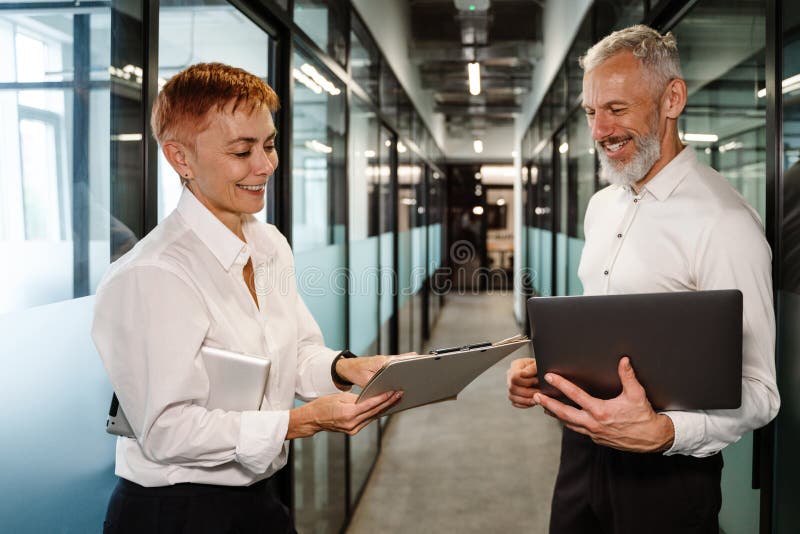 Two Colleagues Talking and Smiling while Working in Office Stock Photo ...