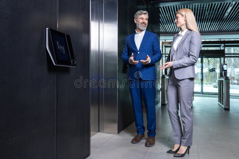 Two Colleagues Talking while Waiting for the Elevator in a Business Center Stock Photo - Image ...