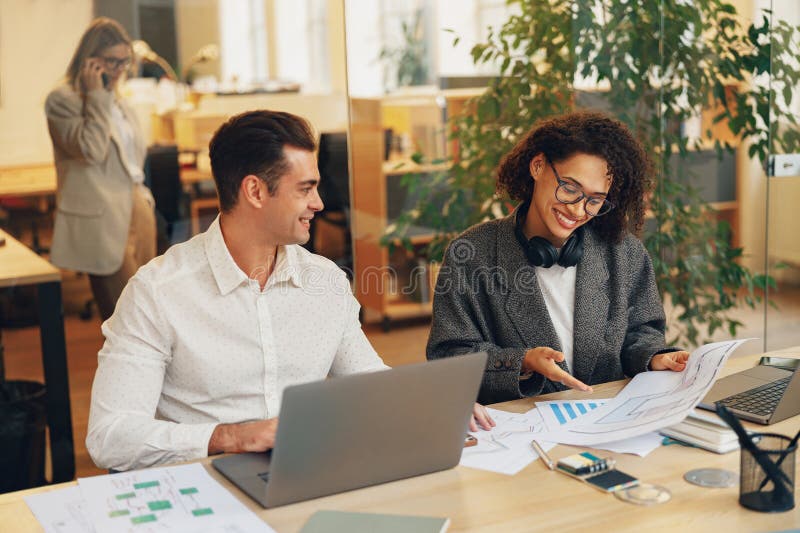 Two Colleagues Working Together with Documents while Sitting on Office ...