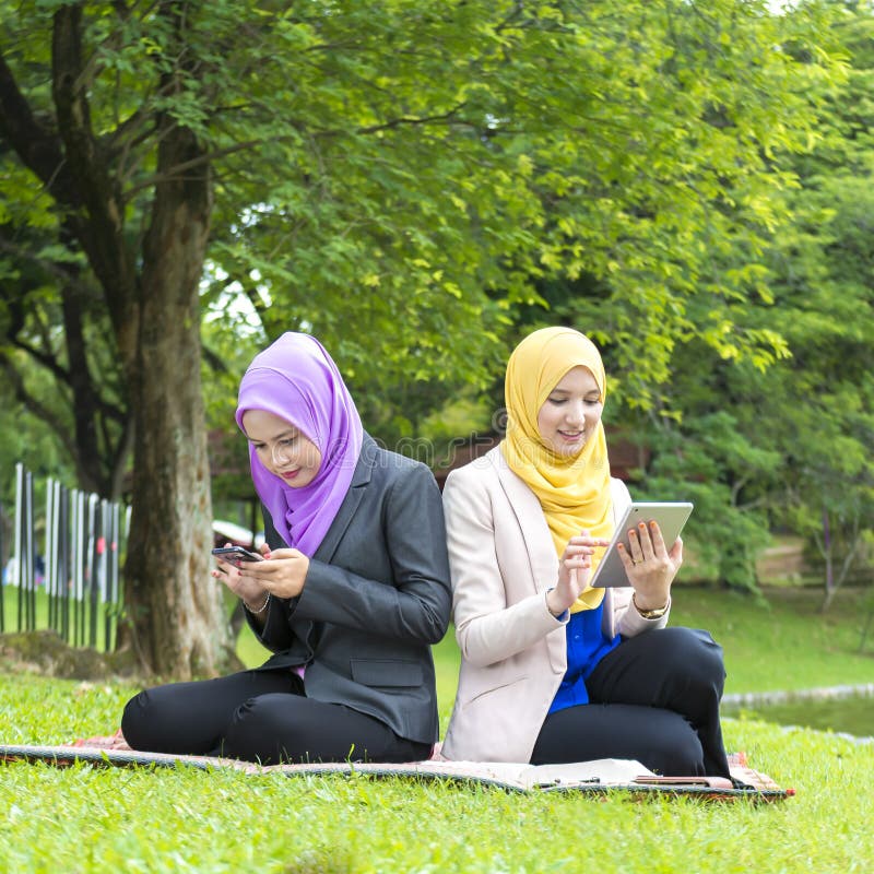 Two College Students Busy Texting with Their Smartphone while Resting ...