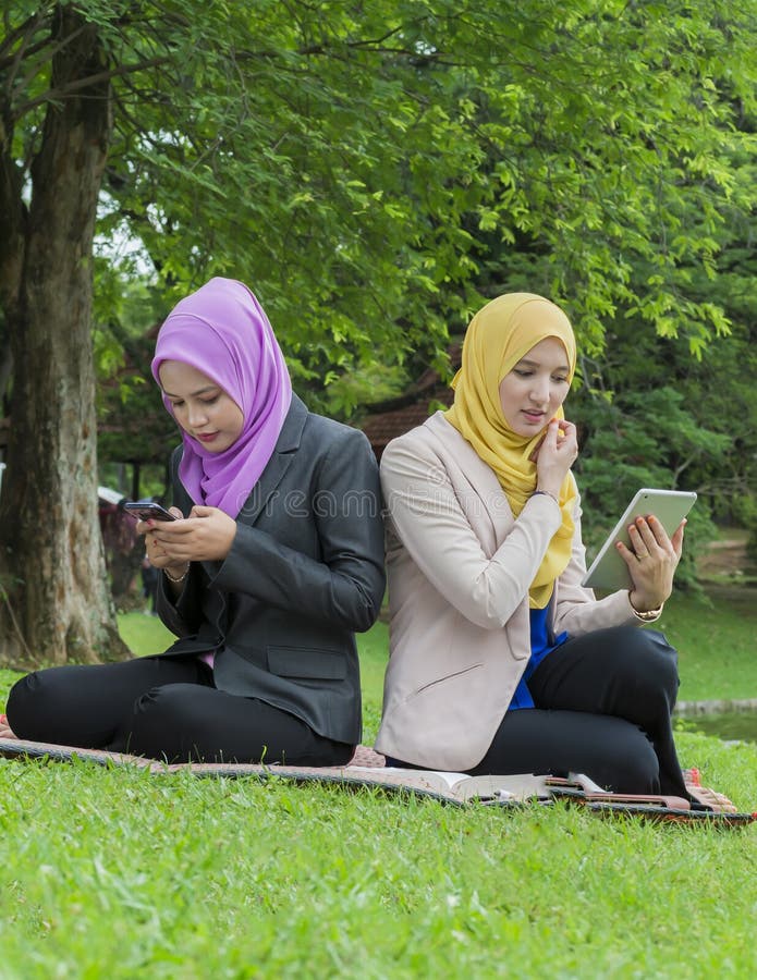 Two College Students Busy Texting with Their Smartphone while Resting ...